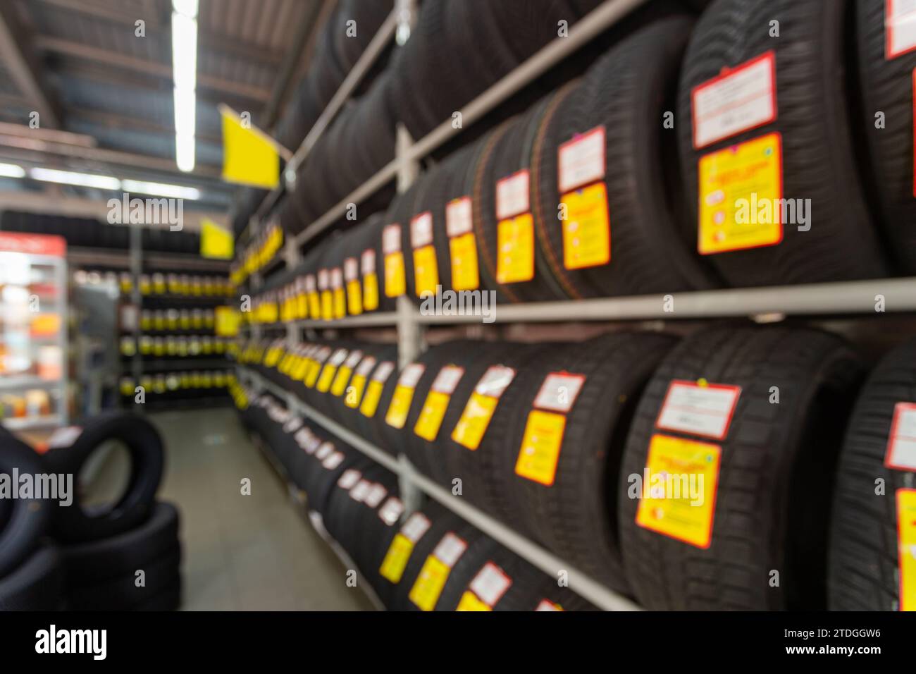 Blurred image rows of brand new tires for sale at retail store. Defocused background interior of ...