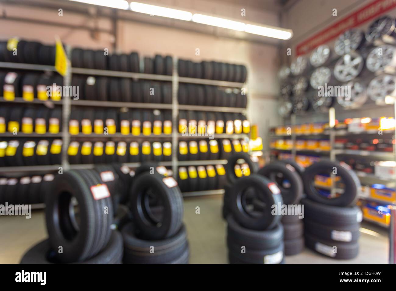 Blurred image rows of brand new tires for sale at retail store. Defocused background interior of ...