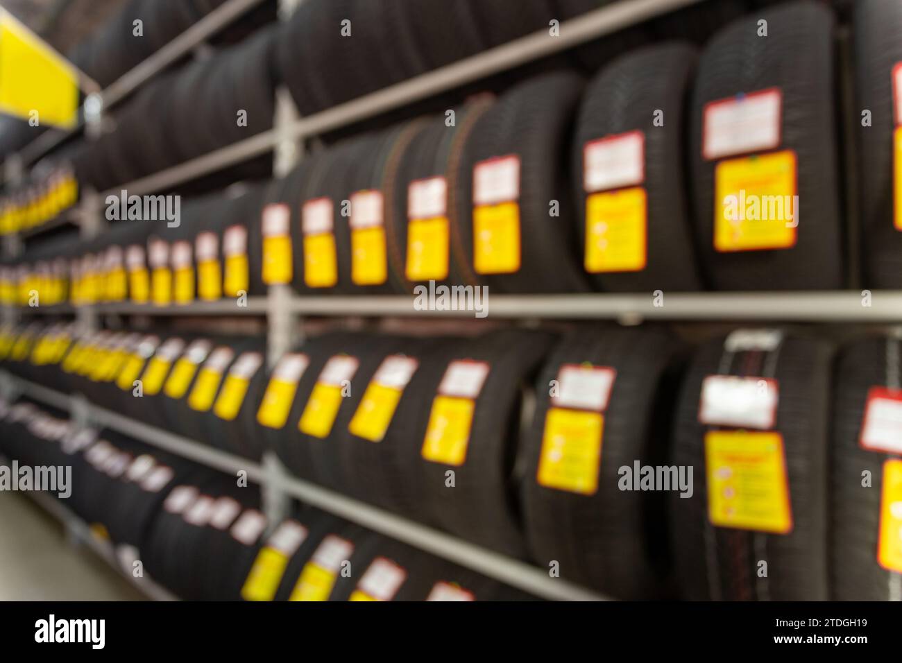 Blurred image rows of brand new tires for sale at retail store. Defocused background interior of ...