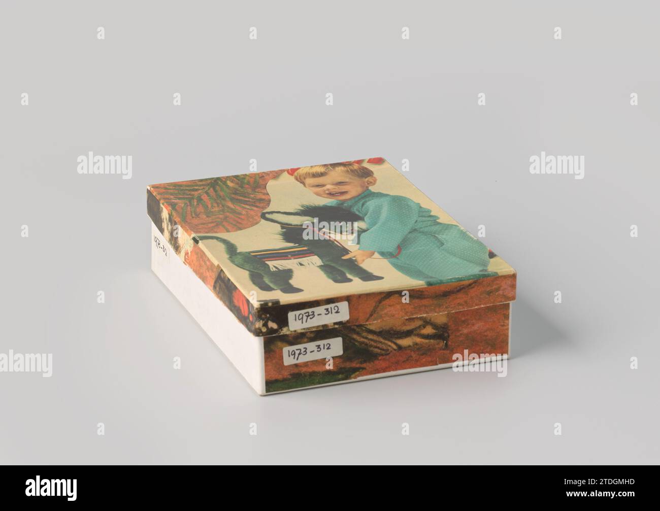 Box with loose lid, made of cardboard with paper on which a toy with a ...