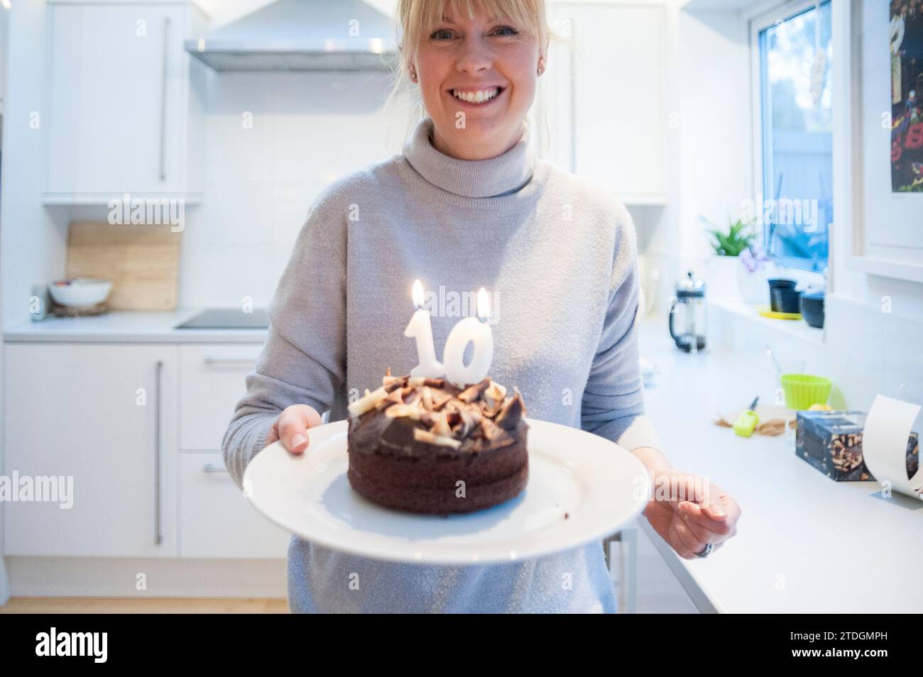 A mother holds a birthday cake for their child's tenth birthday party ...