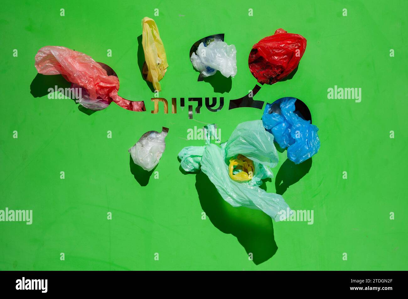 Multi-colored plastic bags protrude from a bright green, metal ...