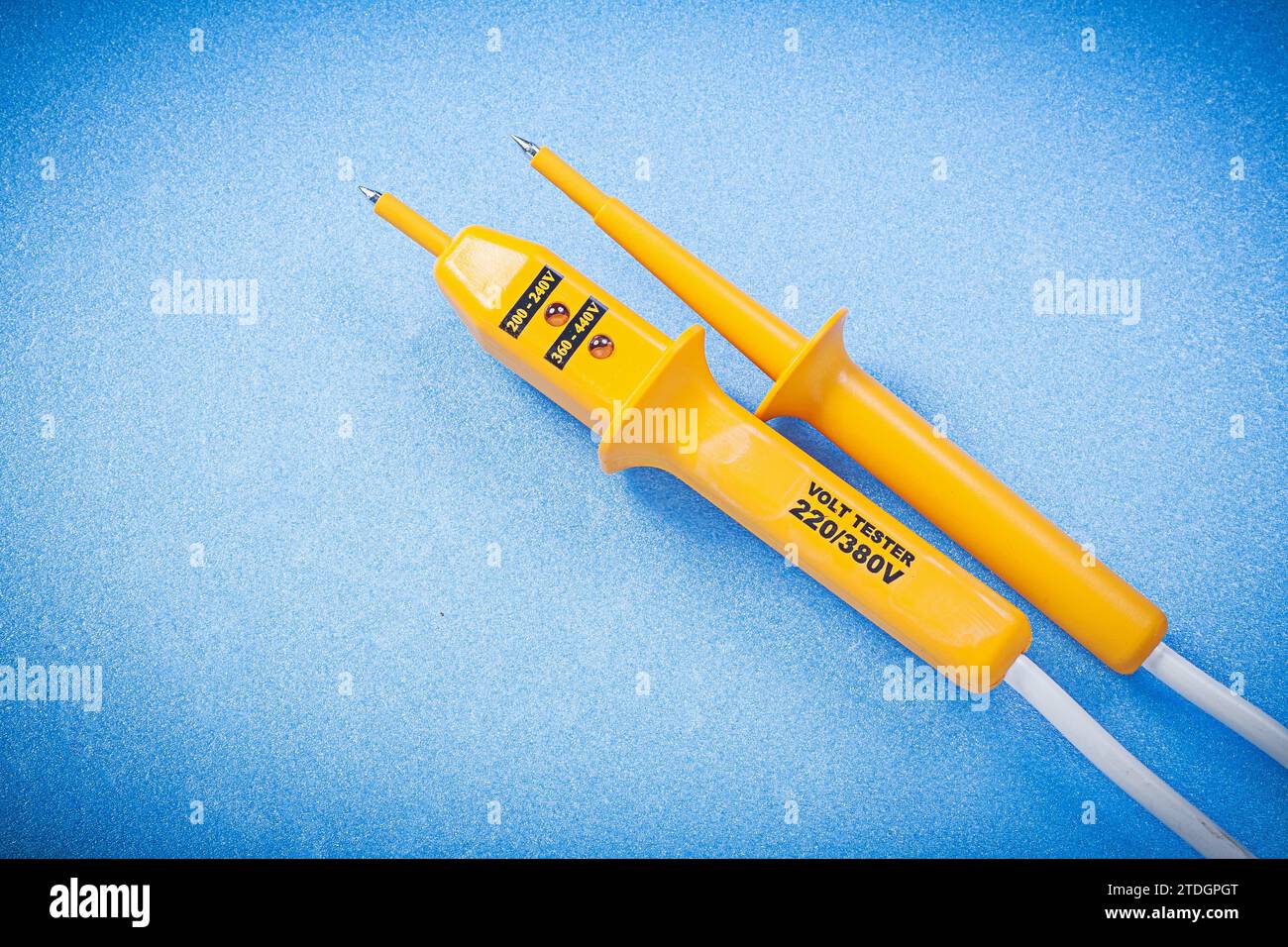 Yellow electrical tester isolated on blue surface electricity concept ...