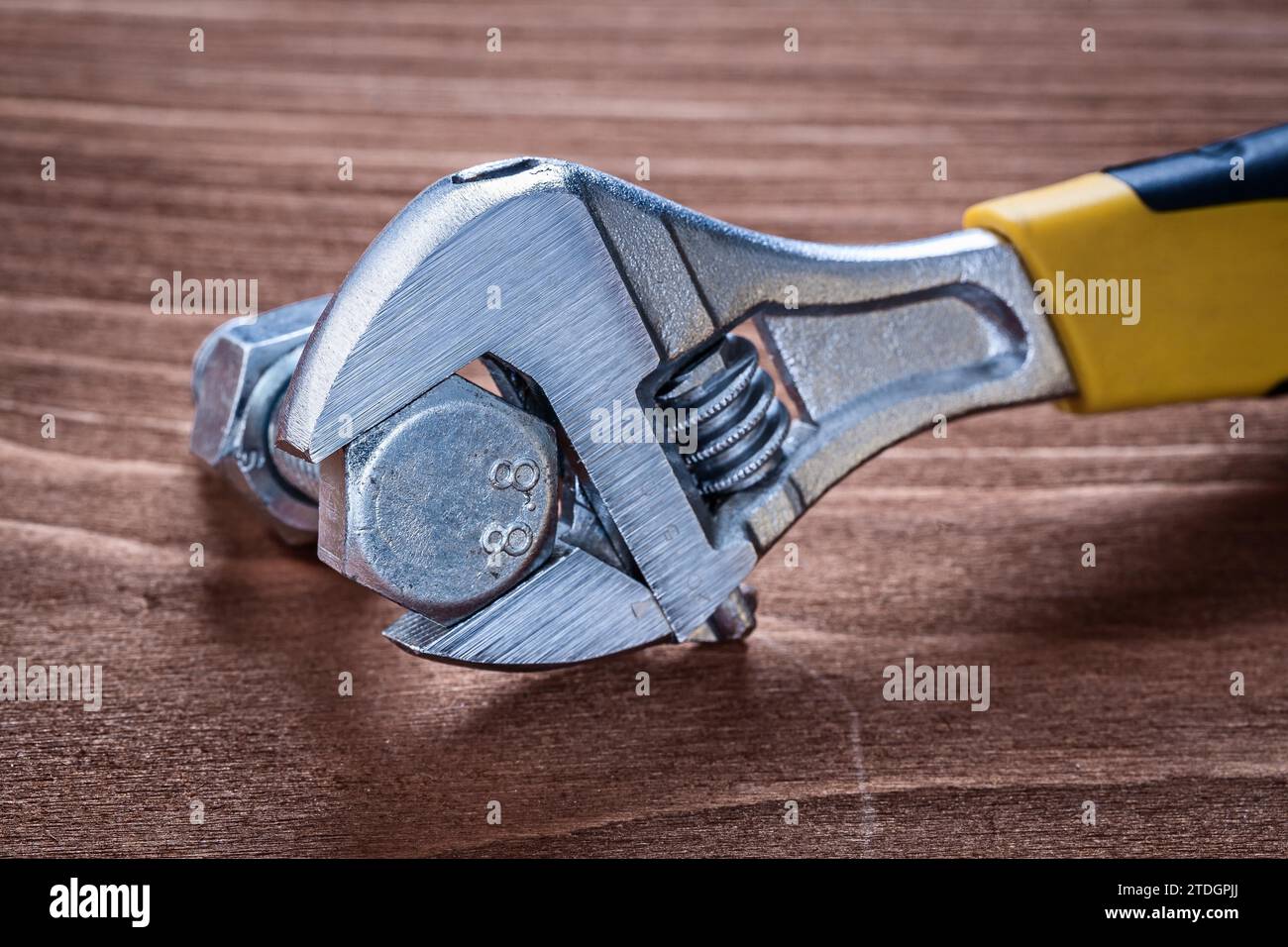 Adjustable spanner stainless bolt and screw nut on brown wooden board ...
