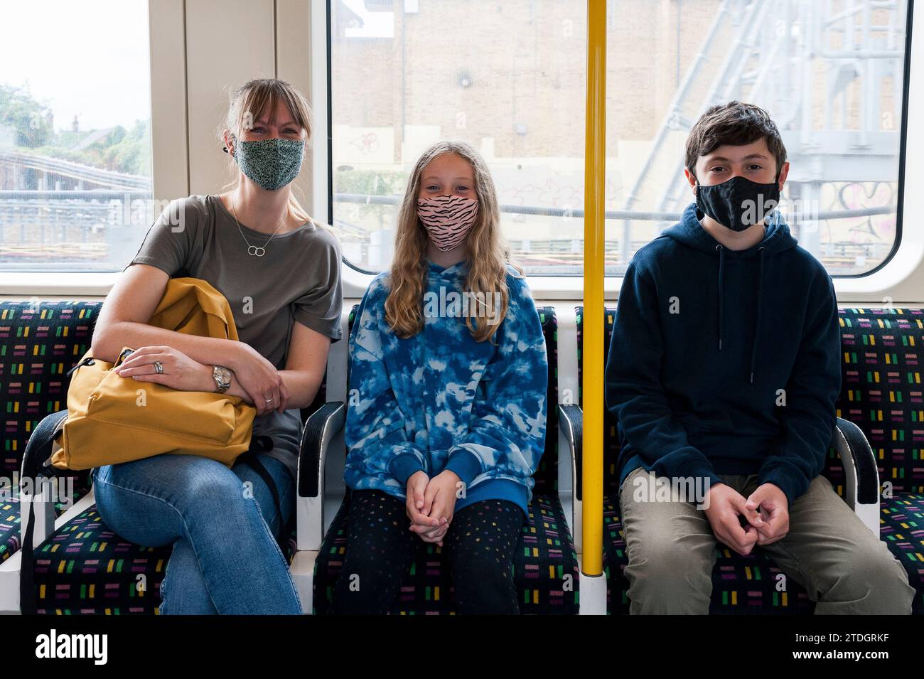 A mother and two children travel on a London Underground train with ...