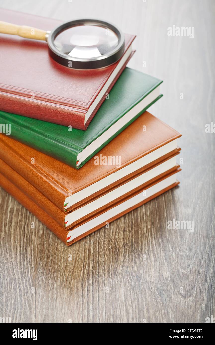 Five notebooks and magnifying glass Stock Photo - Alamy