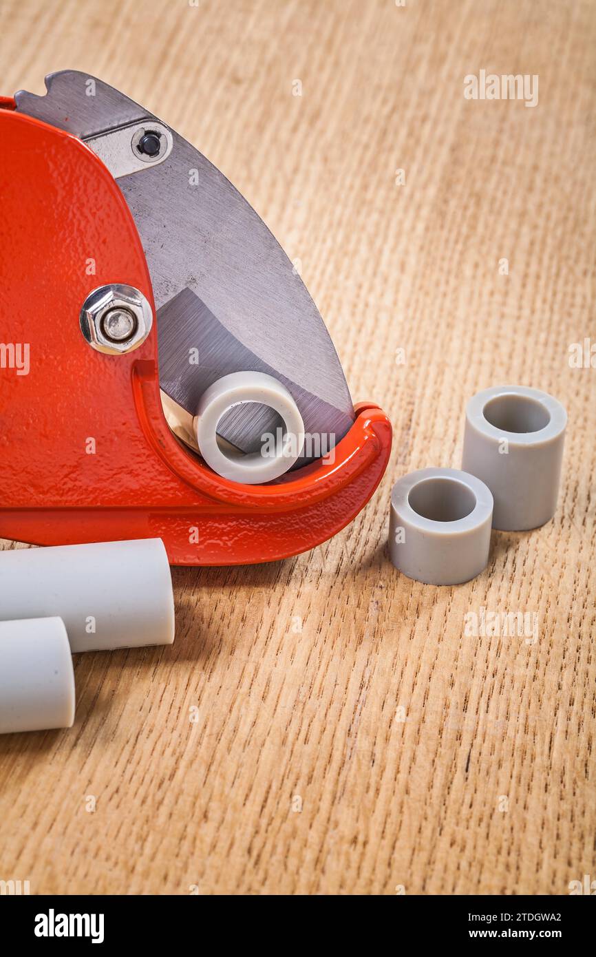 Pipe cutter with pipes on wooden plate Stock Photo - Alamy