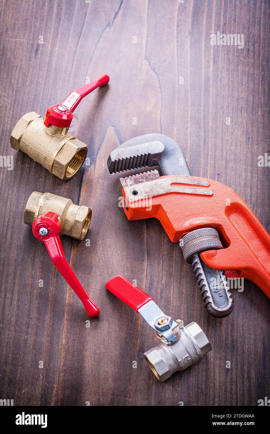 Plumbing accessories and adjustable spanner on an old wooden board ...