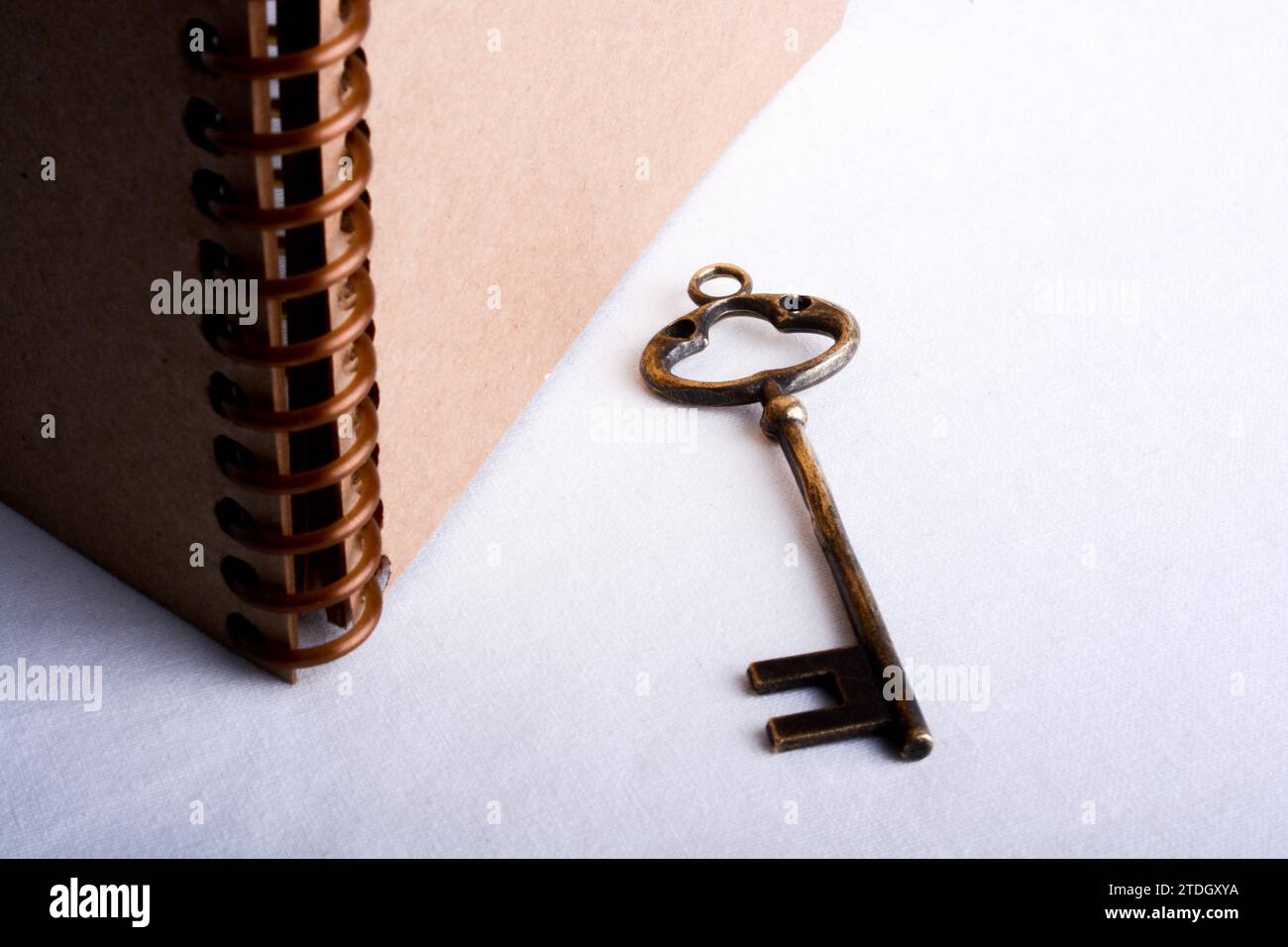 Key by the side of a spiral notebook on a white background Stock Photo ...