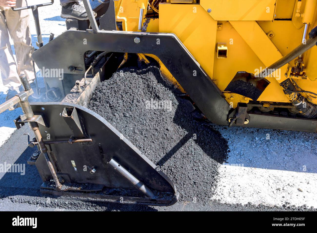 An asphalt paver lays new bitumen asphalt on top of gravel base during ...