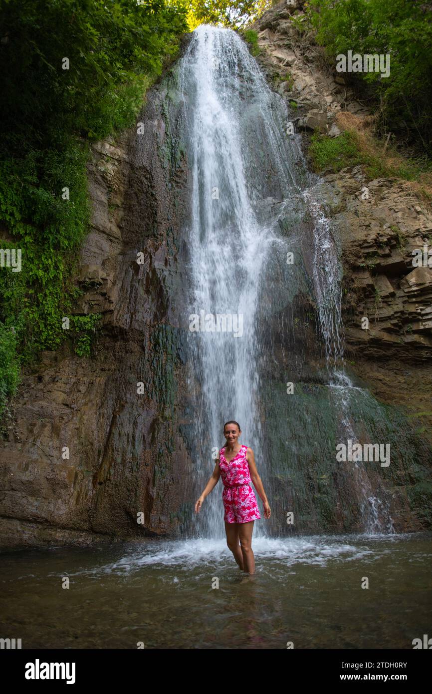 Enchanted Red: Girl in Scarlet under the Waterfall Stock Photo - Alamy