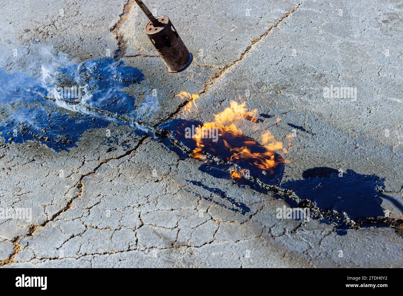 Worker patcher performs work to restore asphalt surfaces by coating ...