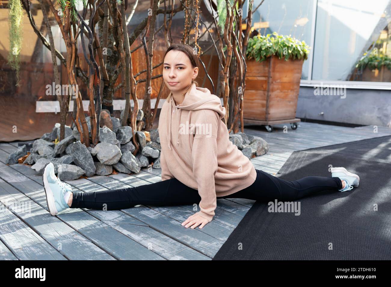 A young attractive girl looks at the camera, plays sports on the street ...