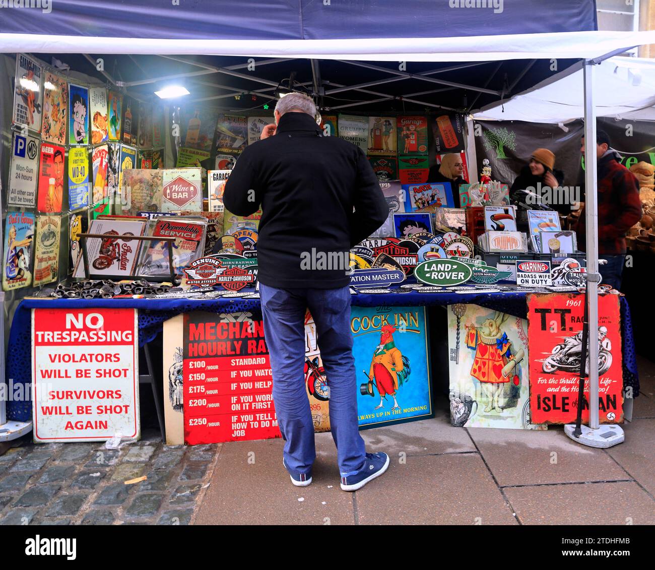 A man looking at a street stall selling vintage signs, Bath. December ...
