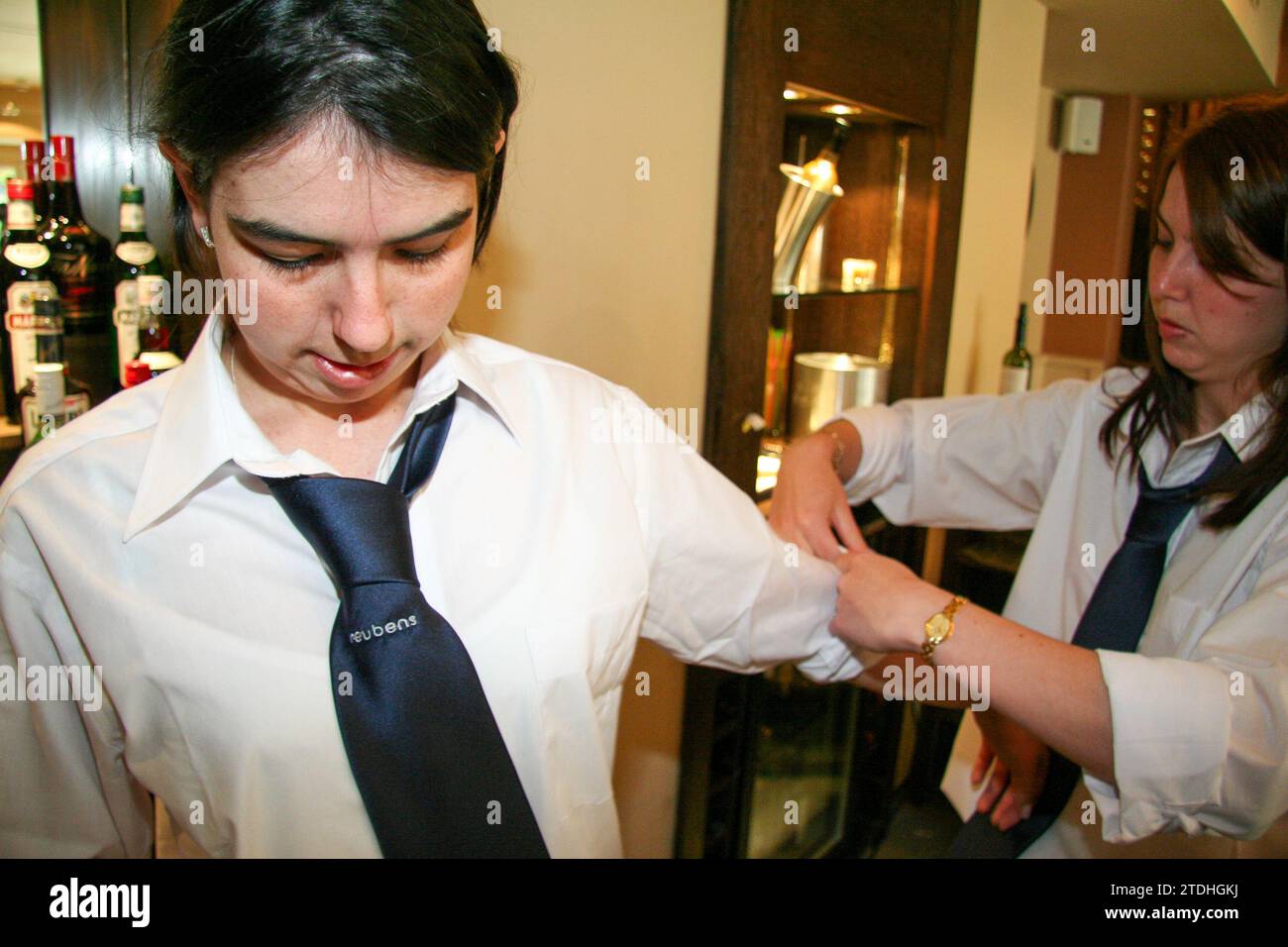 Helping each other first day in new uniforms a waitress/barmaid helps ...