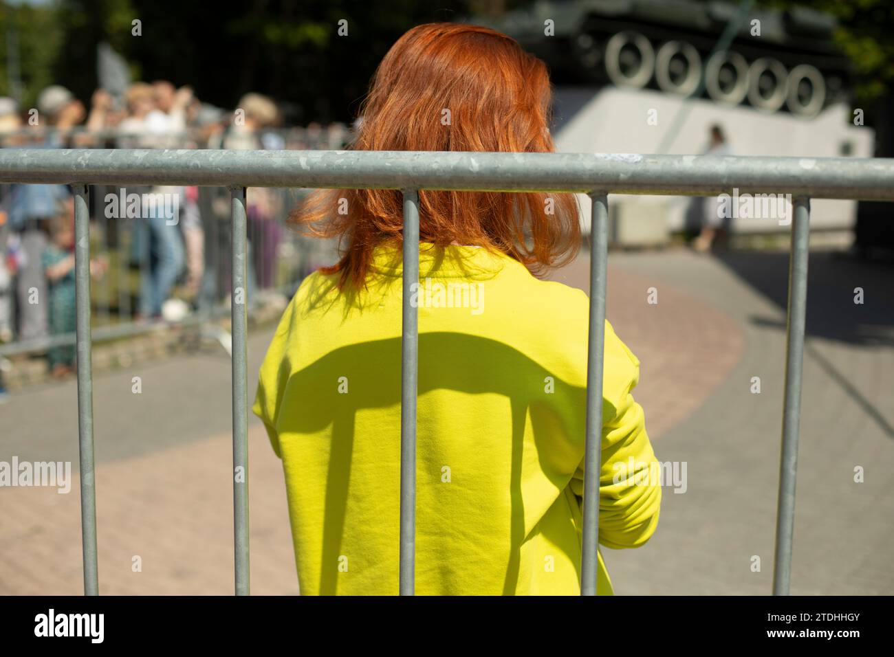 The girl is standing behind the fence. Details of the city event. Fence ...