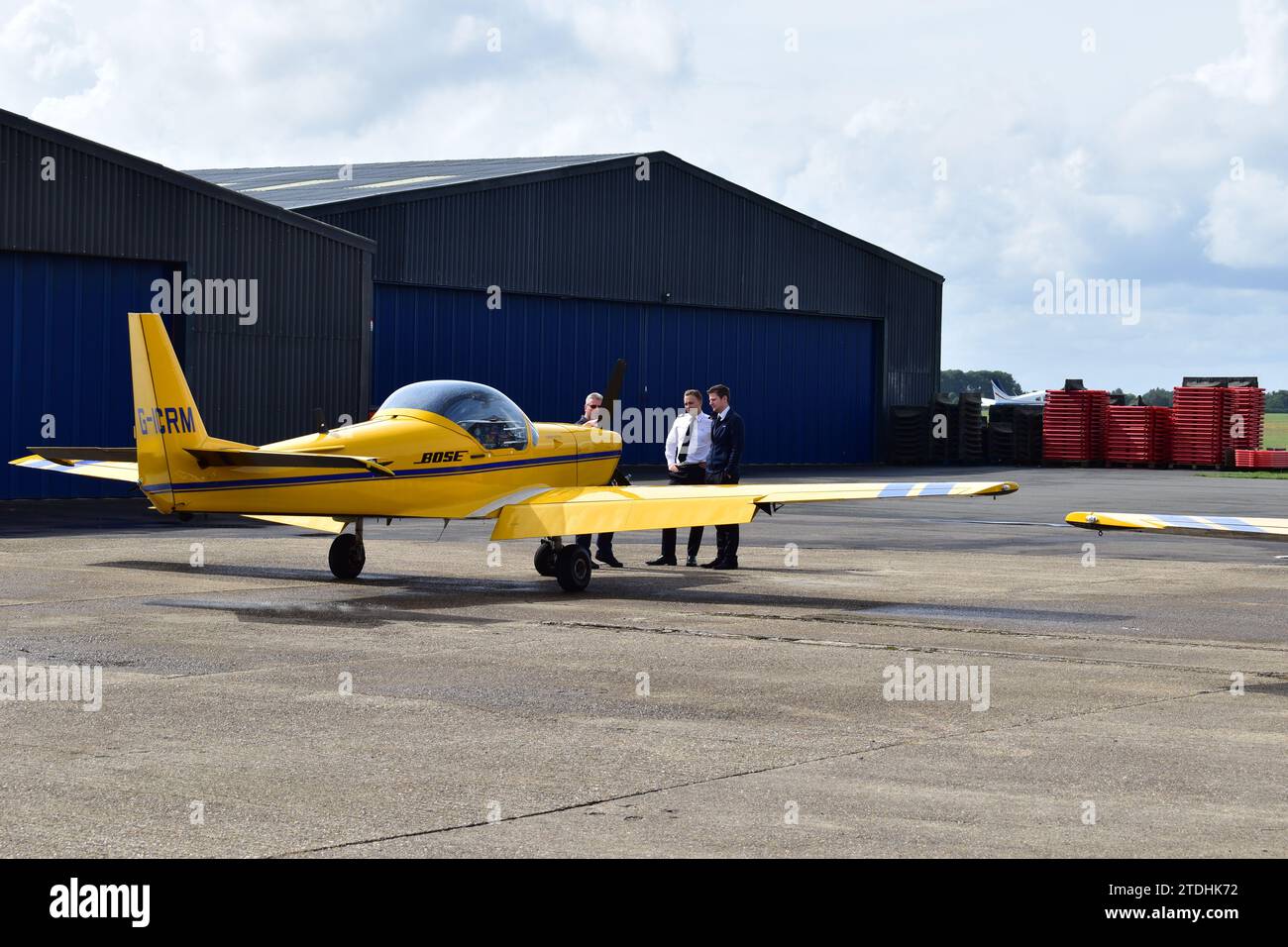 Two students and flight instructor examining a yellow Slingsby Firefly ...