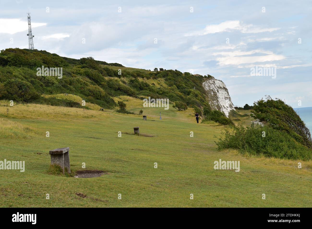 A grass field with several stone benches on the top of the white cliffs ...