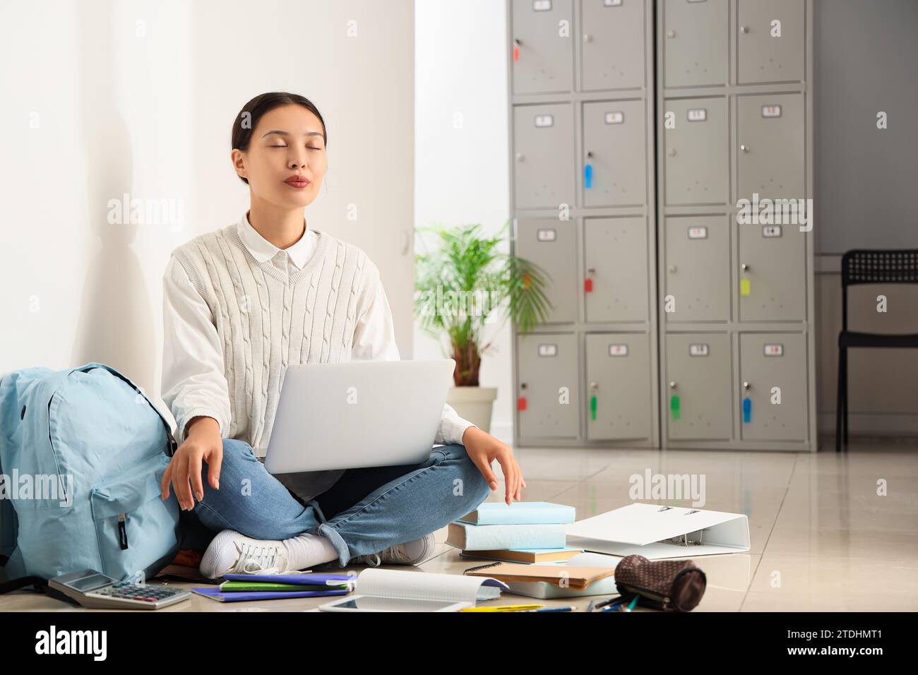 Female Asian student with laptop meditating at university hall Stock ...
