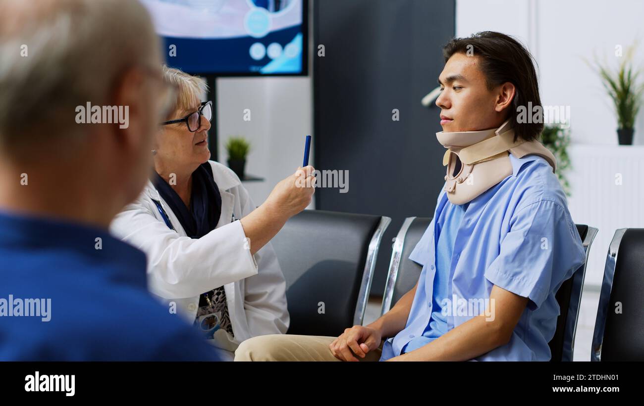Elderly medic examining injured patient, checking eye vision during ...