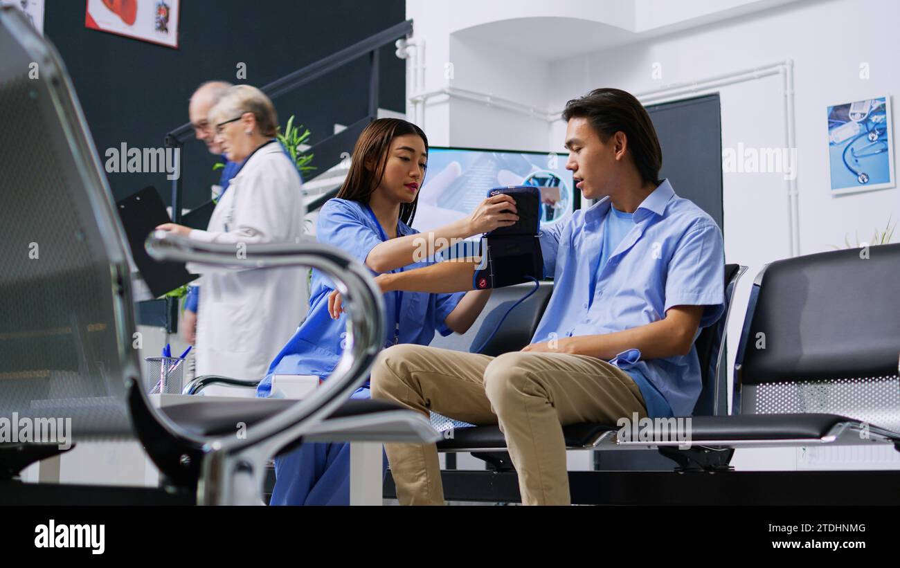 Assistant measuring patient hypertension and blood pressure to do heart ...