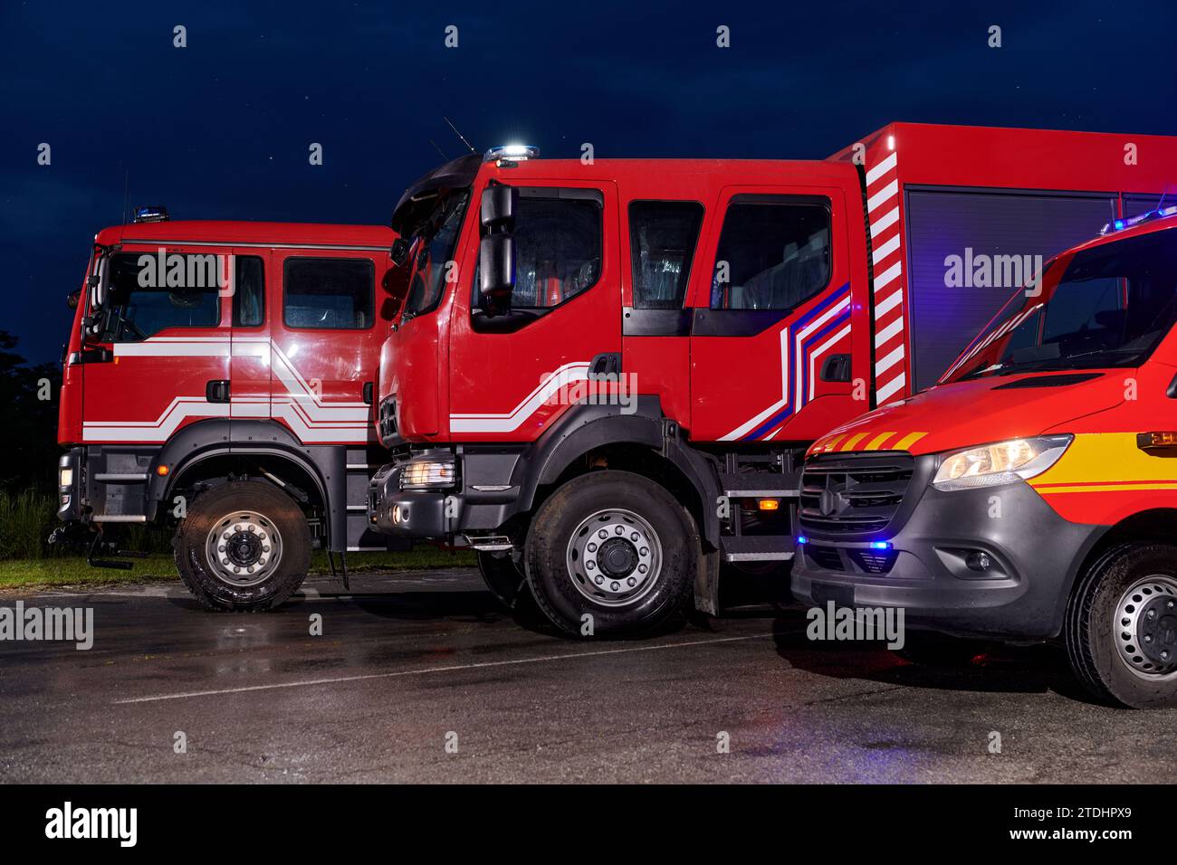 A pair of highly modern and quality fire trucks illuminate the night ...
