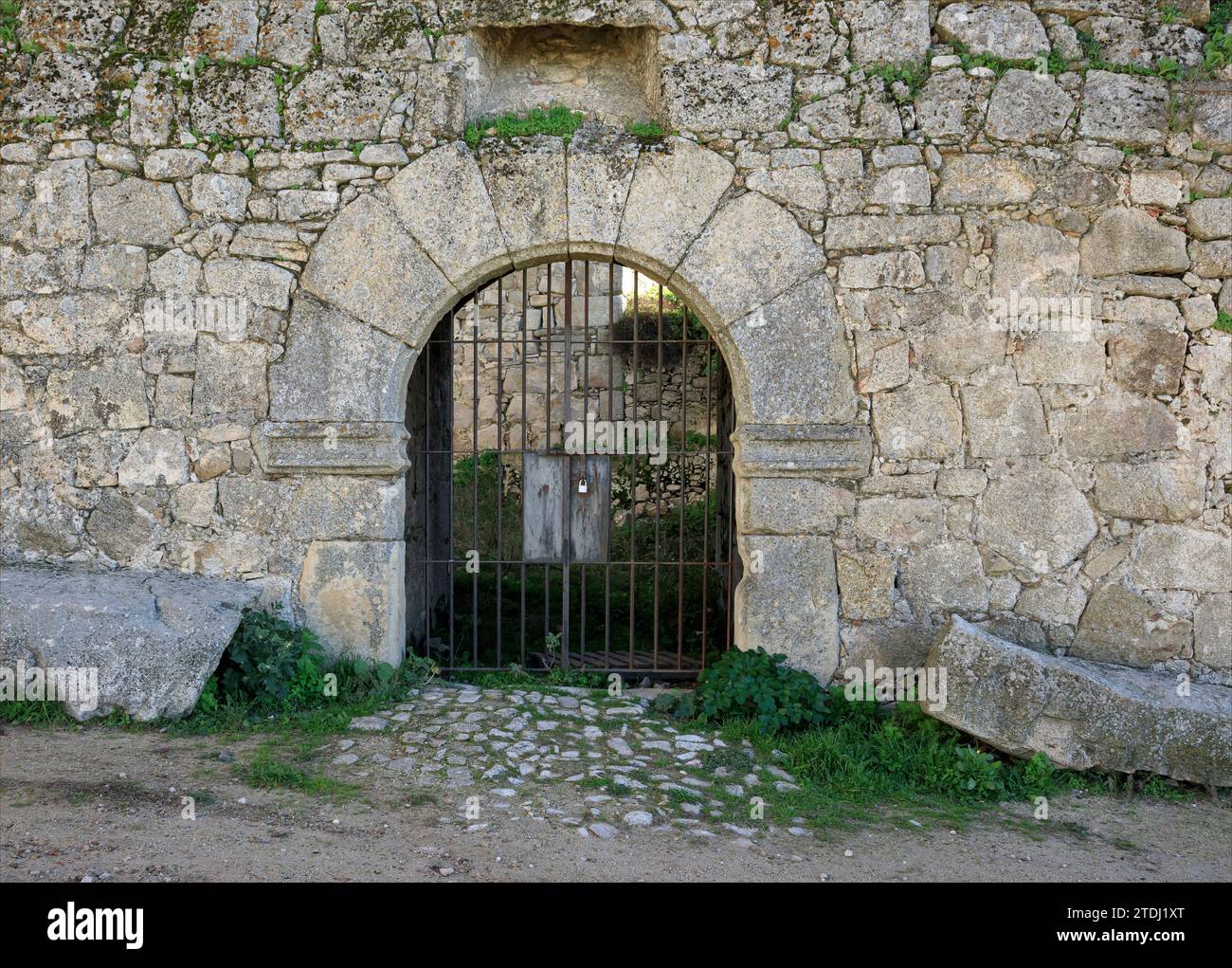 Arched gateway with iron bars which can be seen through which is locked ...