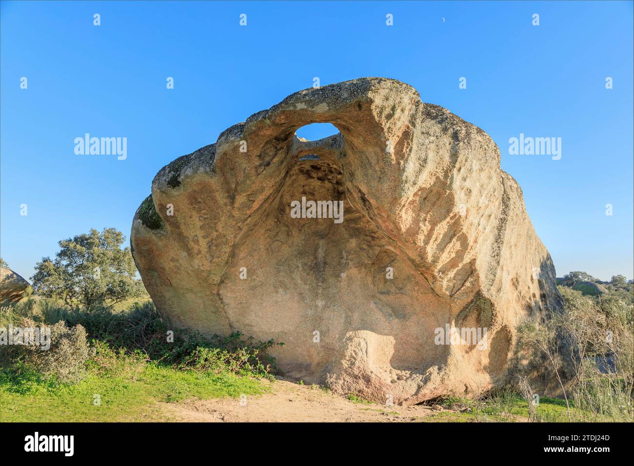 Unique granite boulder with a hole worn through revealing the blue sky ...