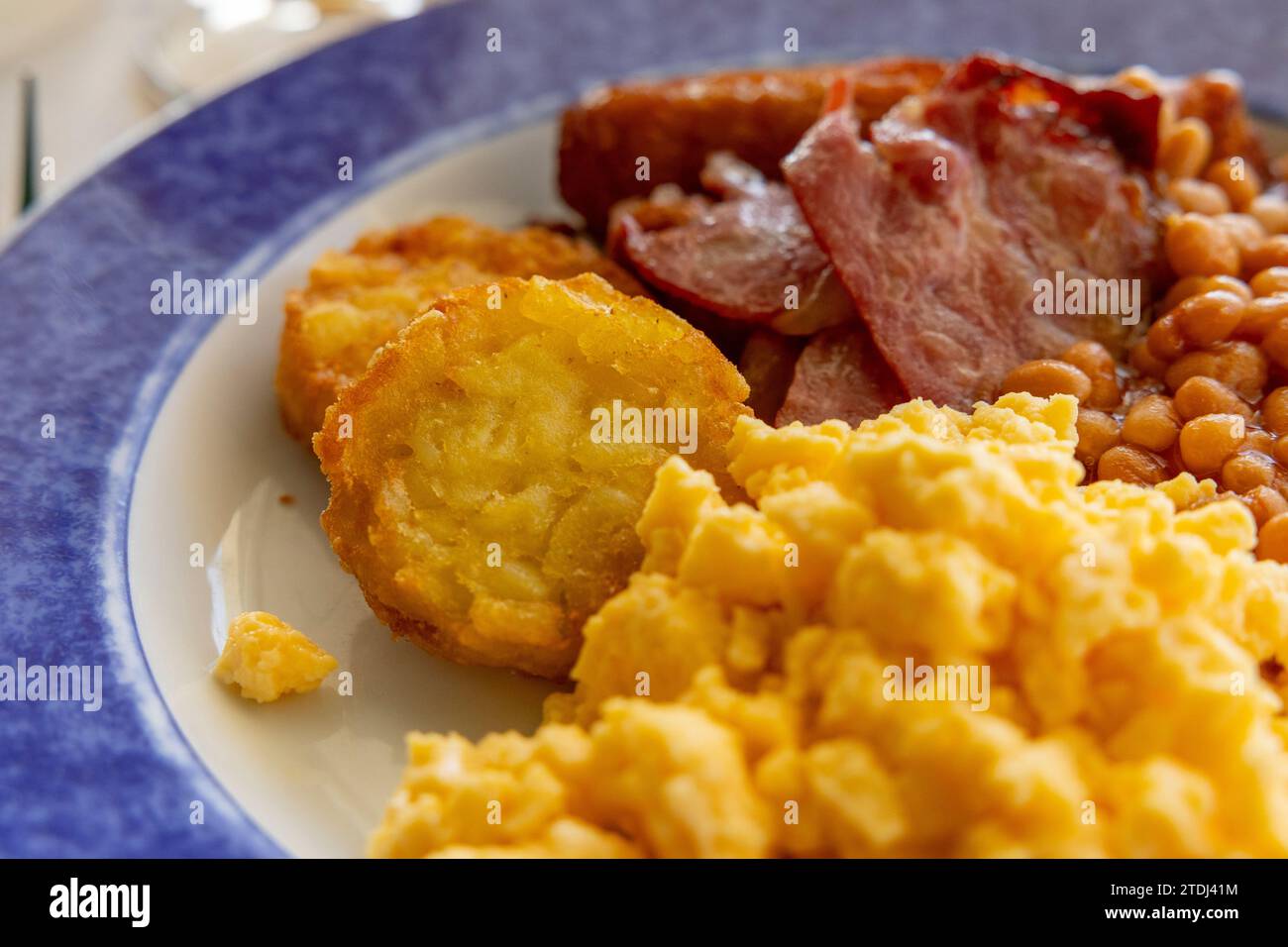 English breakfast with crispy hash brown patties, bacon, scrambled eggs ...