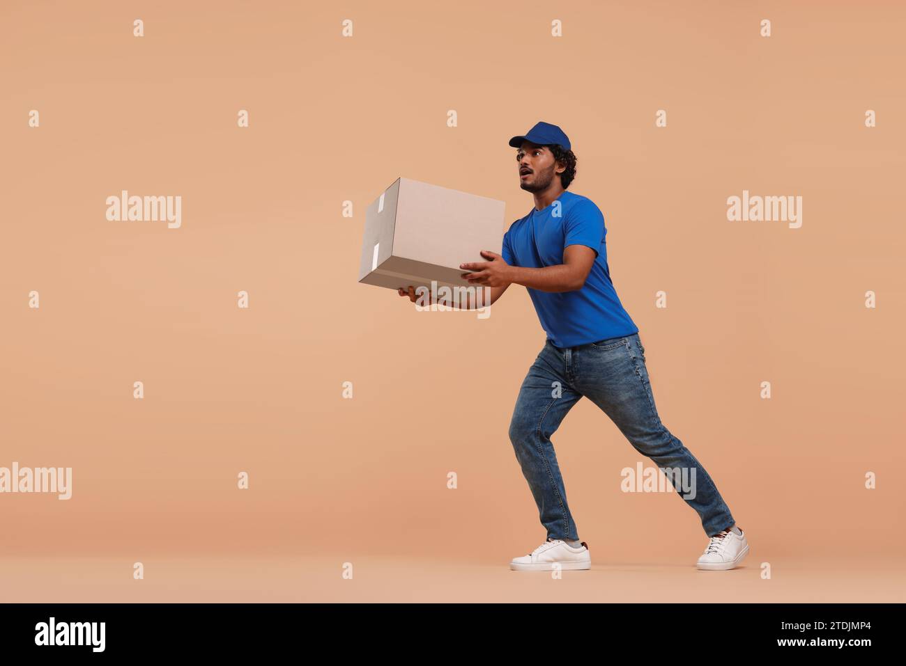 Courier running to deliver parcel on light brown background, space for ...