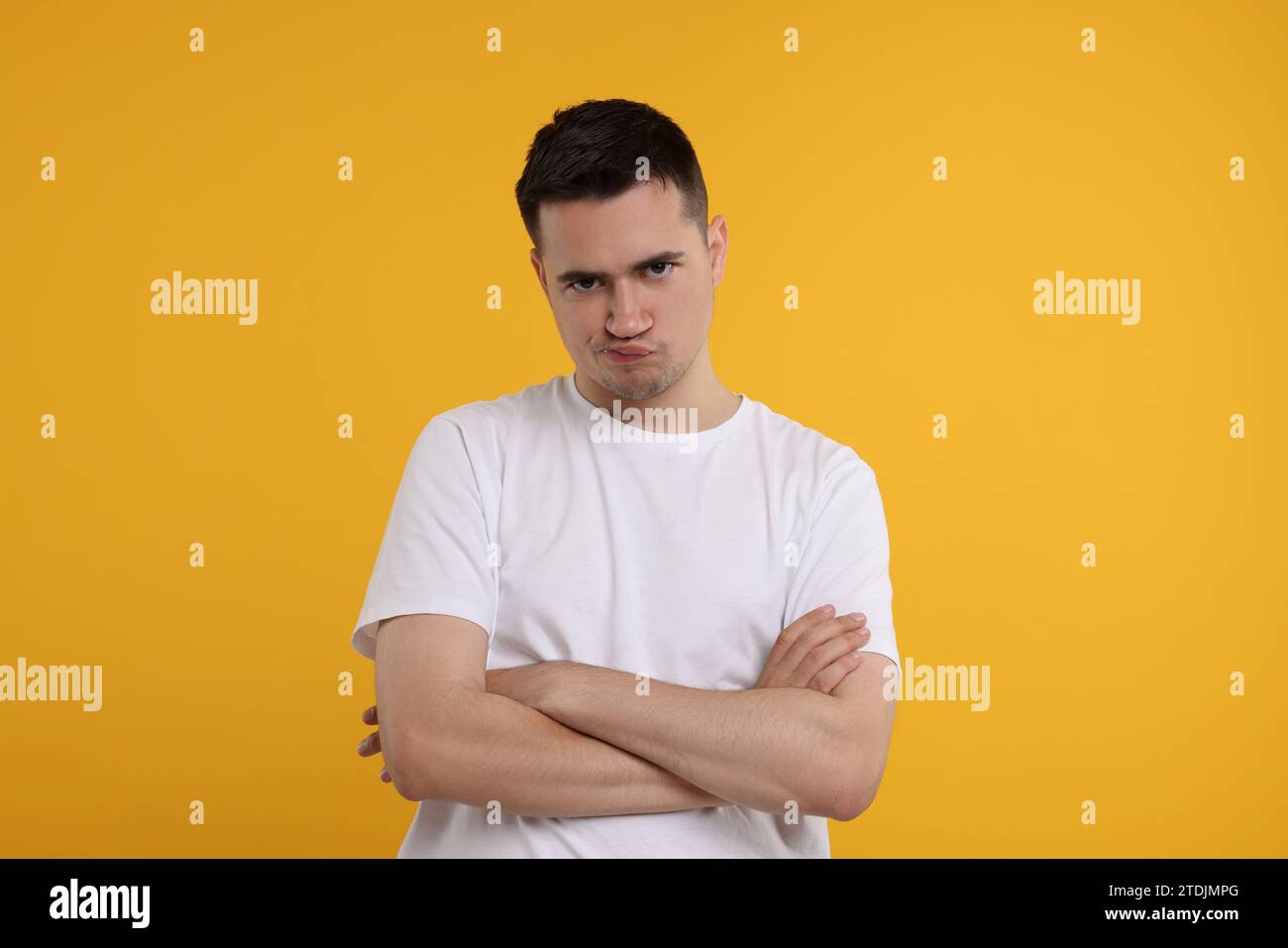 Resentful man with crossed arms on orange background Stock Photo - Alamy