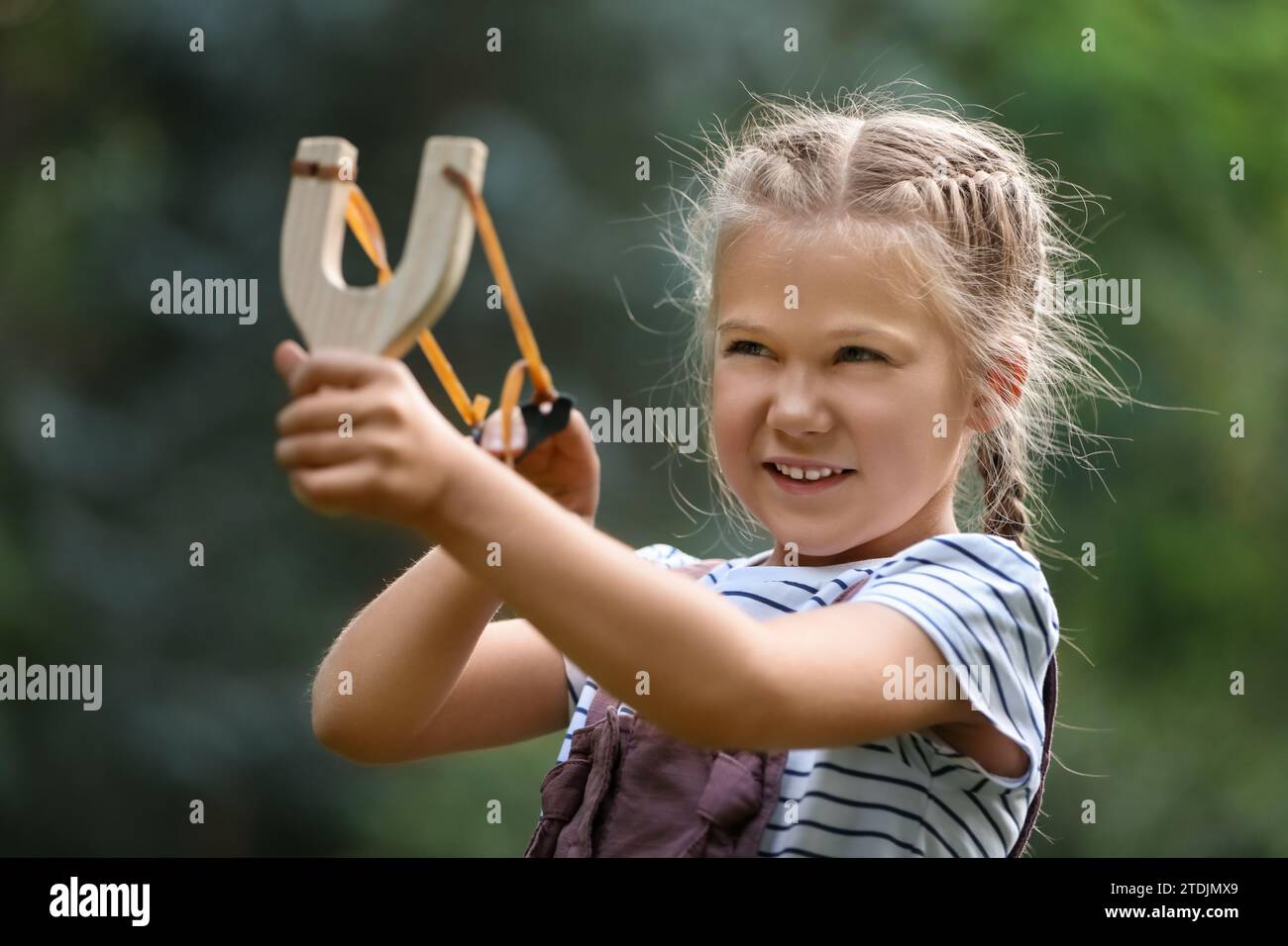 Little girl playing with slingshot in park Stock Photo - Alamy