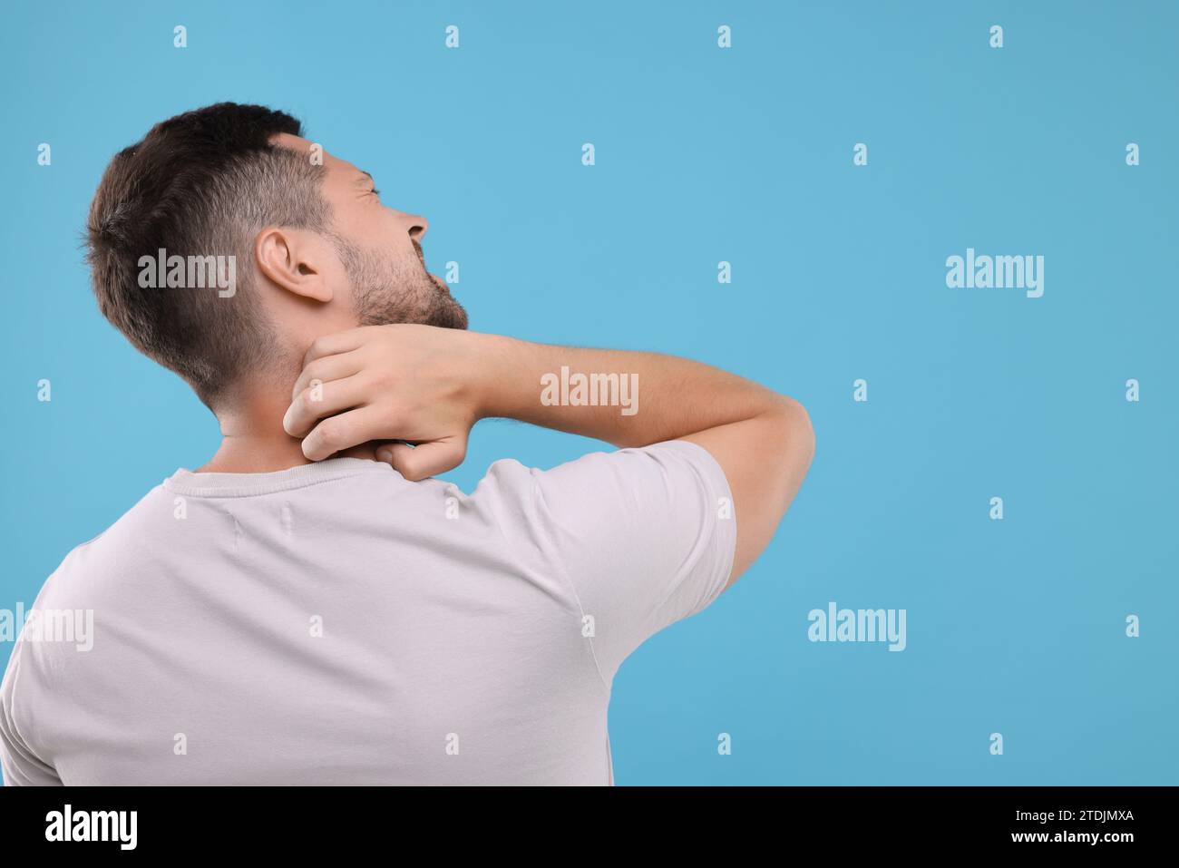 Allergy symptom. Man scratching his neck on light blue background ...