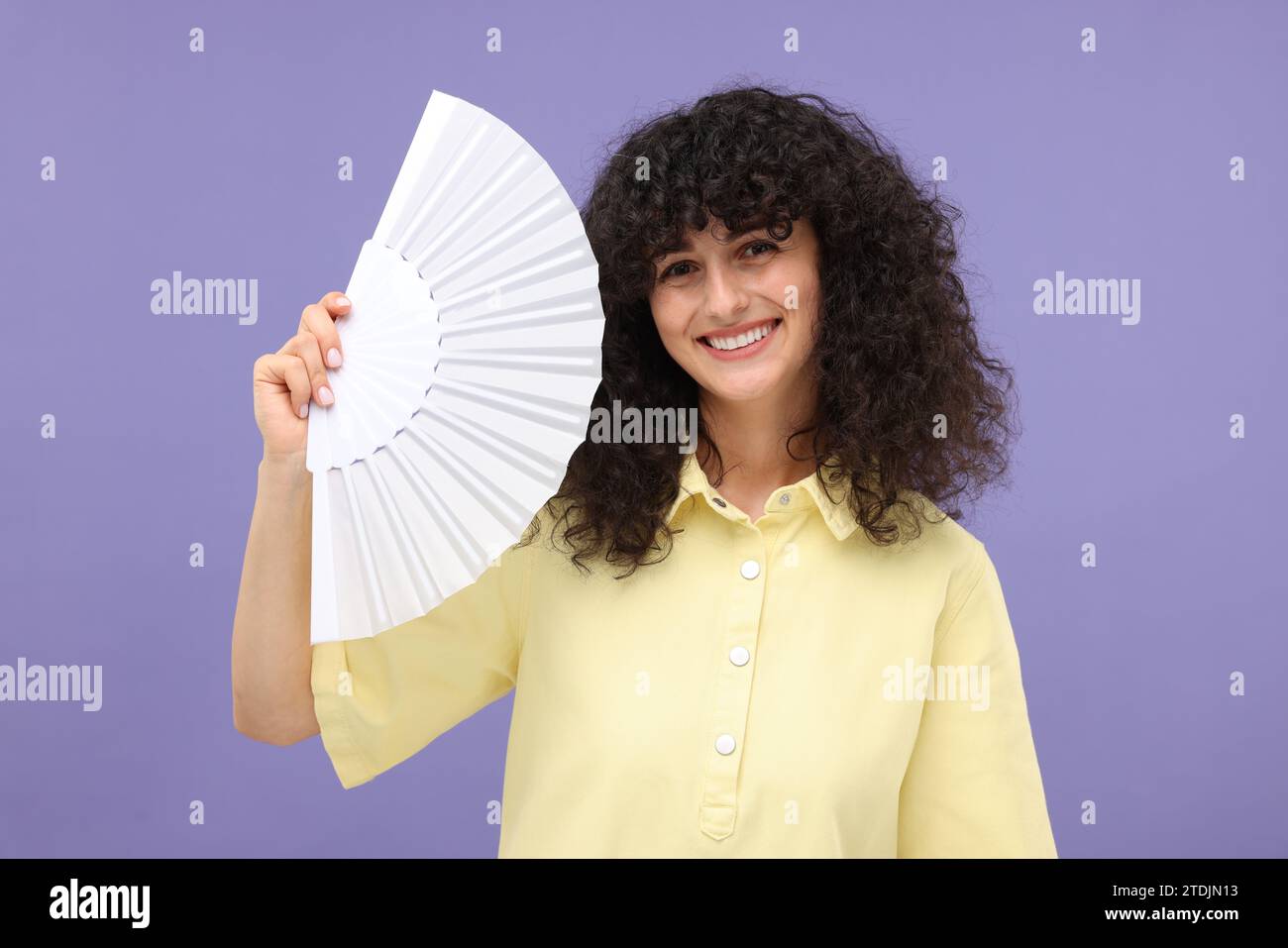 Happy woman holding hand fan on purple background Stock Photo - Alamy