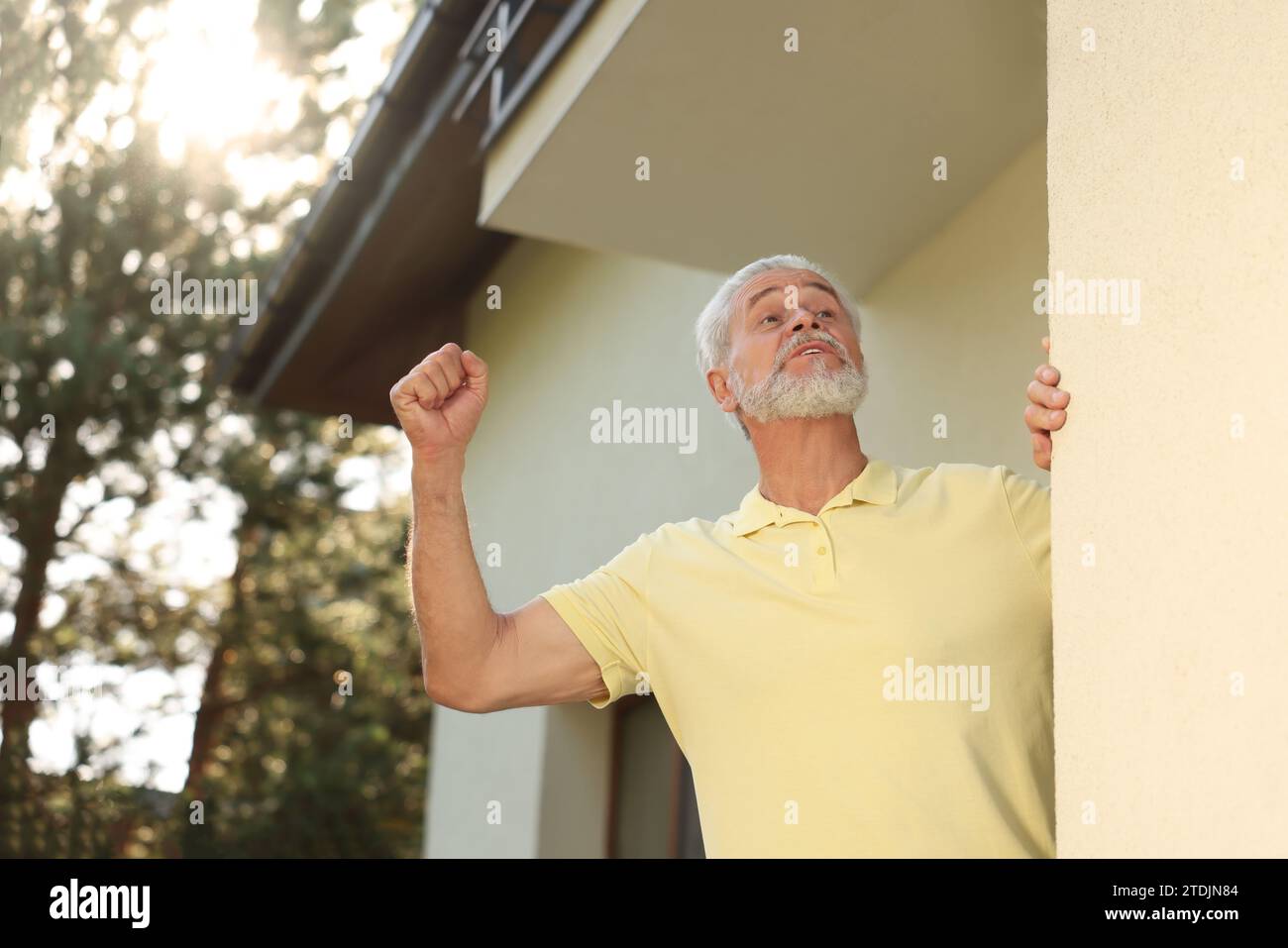 Angry senior man showing fist near house, low angle view. Annoying ...