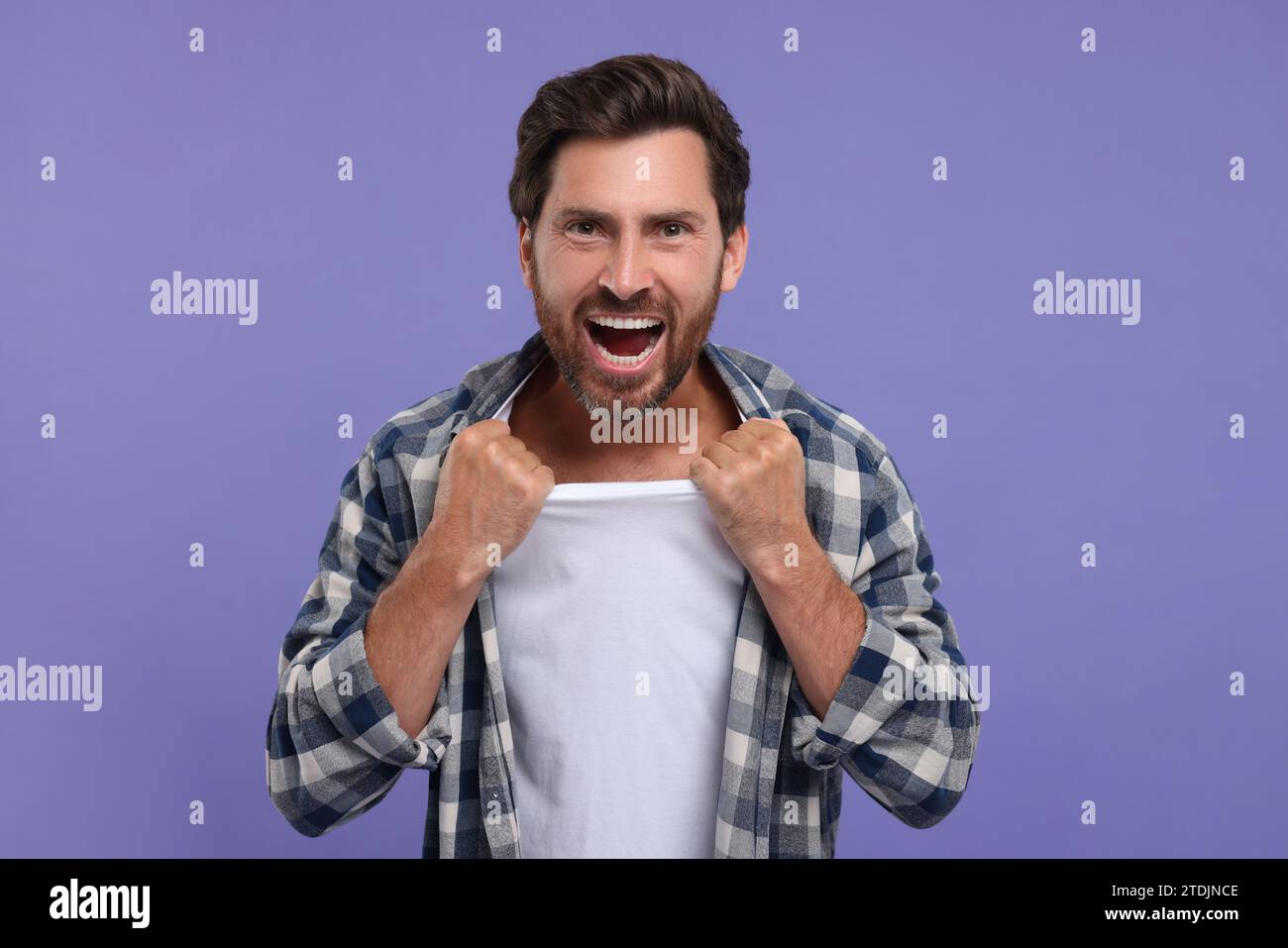 Emotional sports fan celebrating on purple background Stock Photo - Alamy