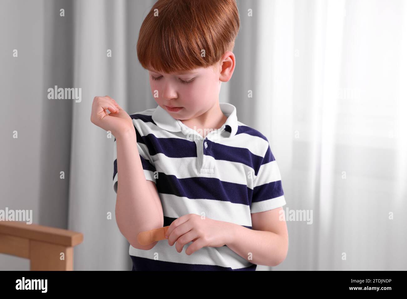 Little boy putting sticking plaster onto elbow indoors Stock Photo - Alamy
