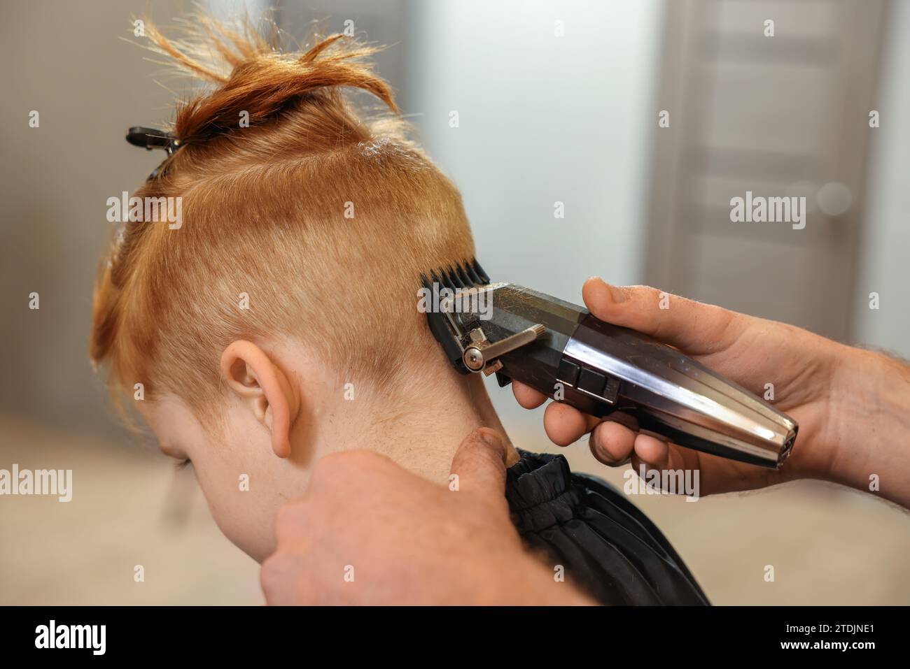 Professional hairdresser cutting boy's hair in beauty salon, closeup ...