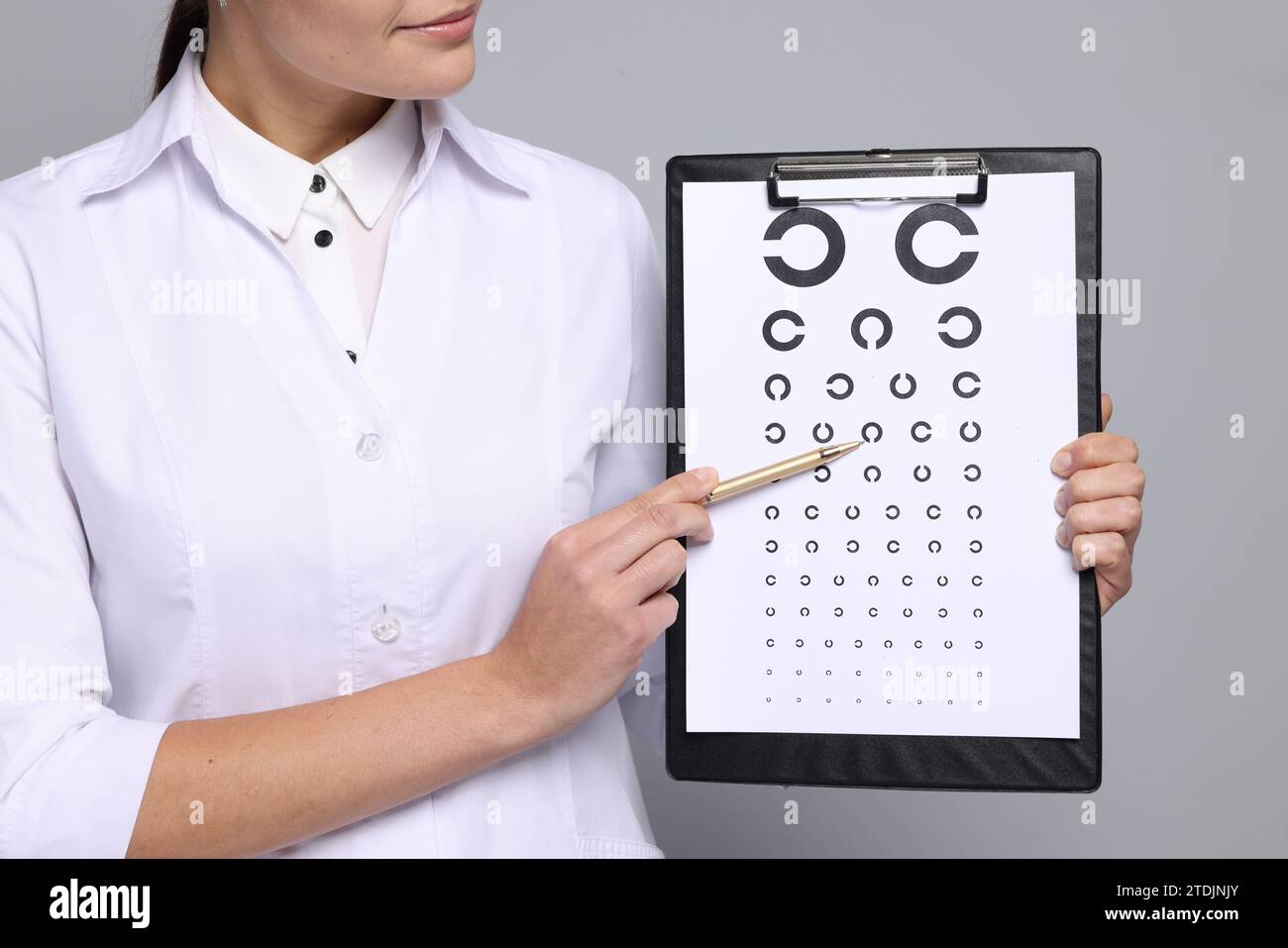 Ophthalmologist pointing at vision test chart on gray background ...