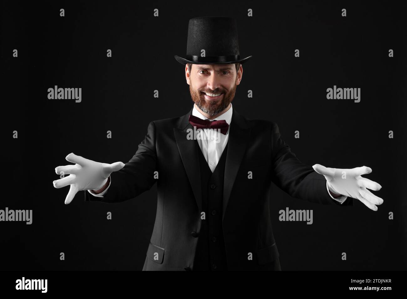 Happy magician in top hat on black background Stock Photo - Alamy