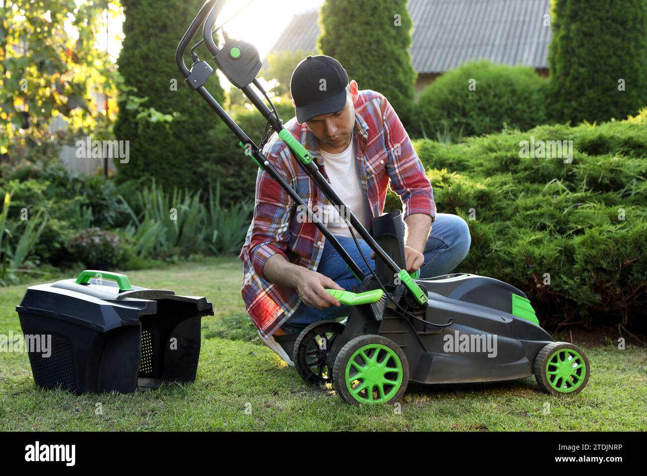 Man cleaning lawn mower with brush in garden Stock Photo - Alamy