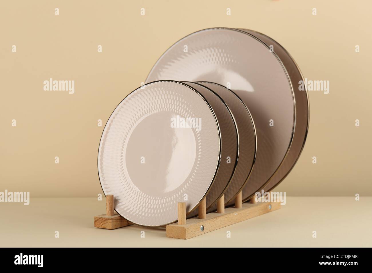 Drying rack with beige ceramic plates on pale yellow table Stock Photo ...
