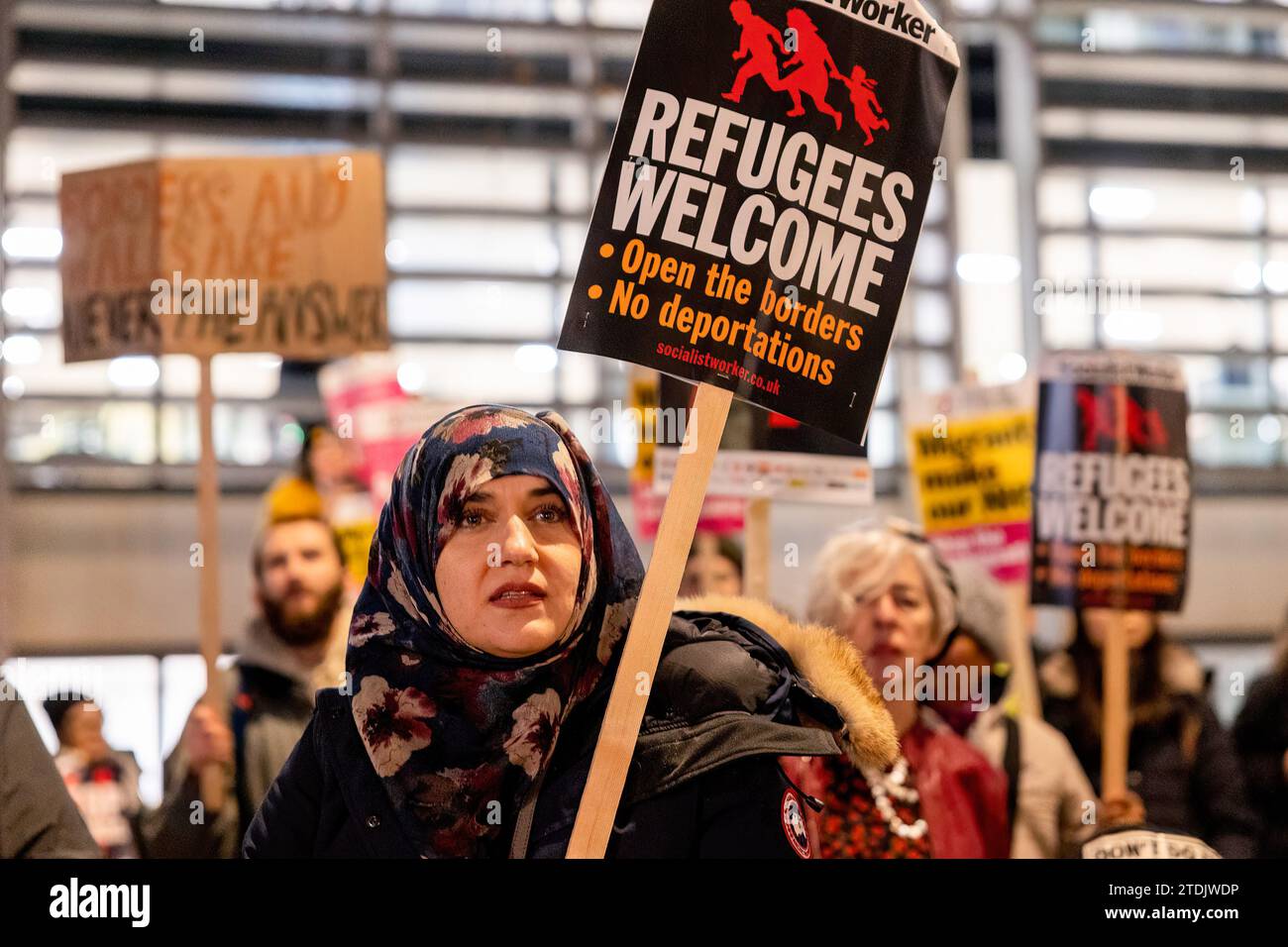 London, UK. 18th Dec, 2023. A woman holds a placard to support refugees ...