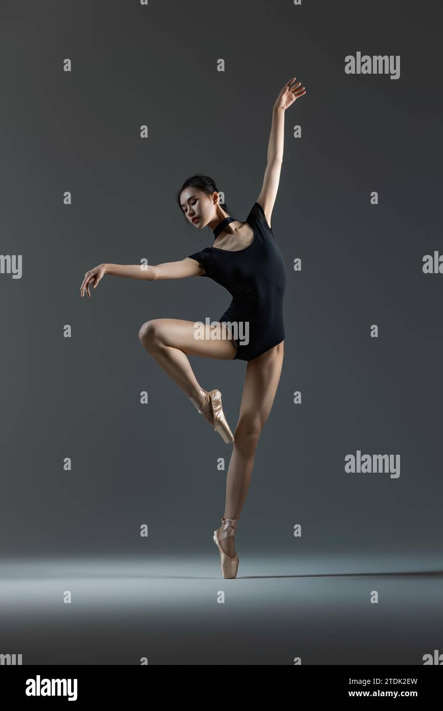 A beautiful young dancer is dancing ballet in the studio with a beam of ...