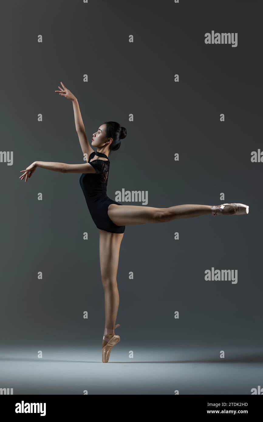 A beautiful young dancer is dancing ballet in the studio with a beam of ...