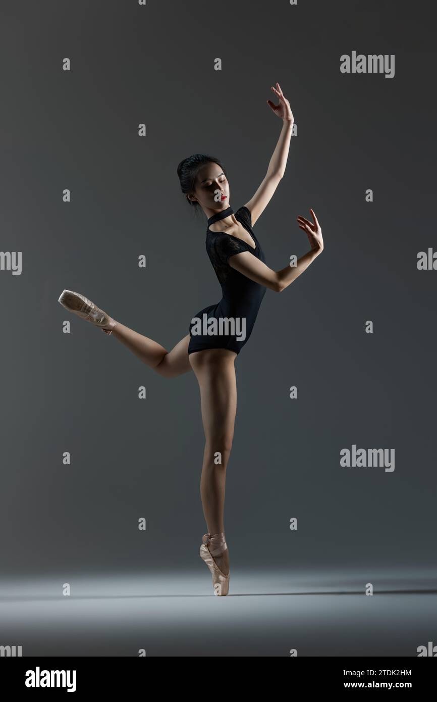 A beautiful young dancer is dancing ballet in the studio with a beam of ...