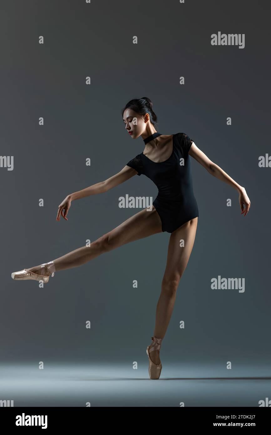 A beautiful young dancer is dancing ballet in the studio with a beam of ...