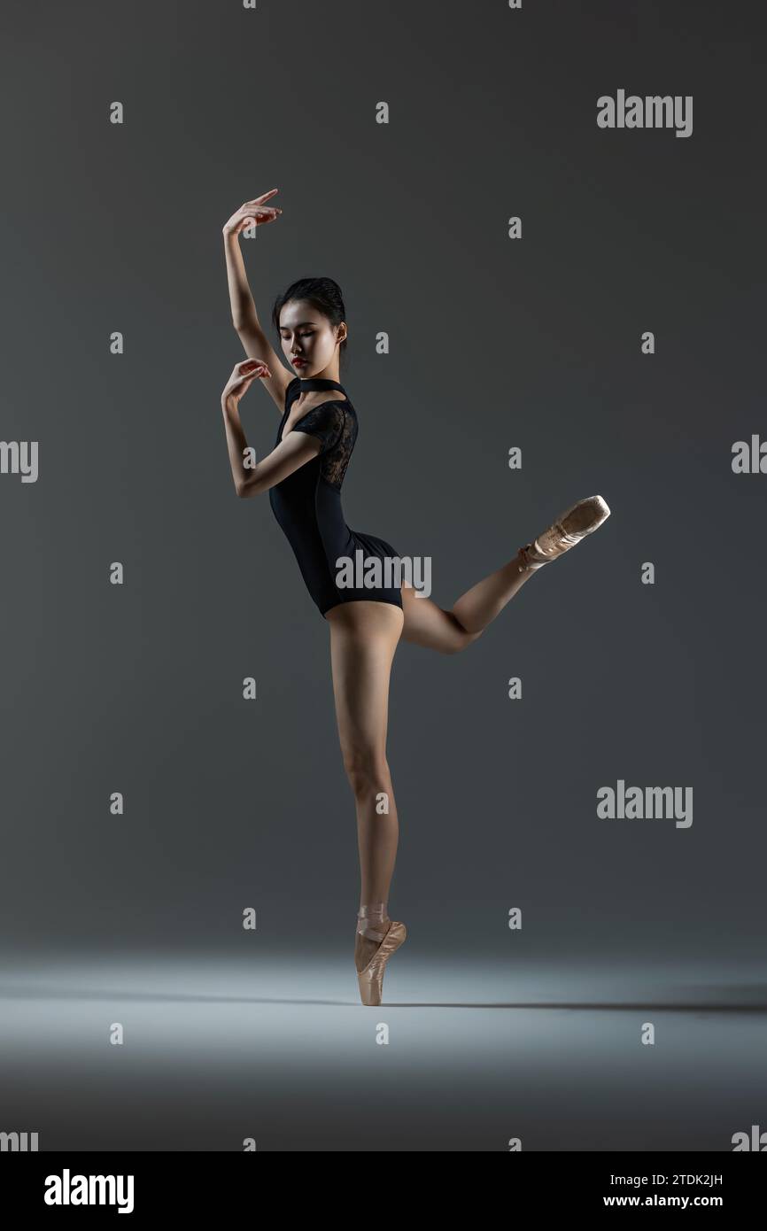 A beautiful young dancer is dancing ballet in the studio with a beam of ...