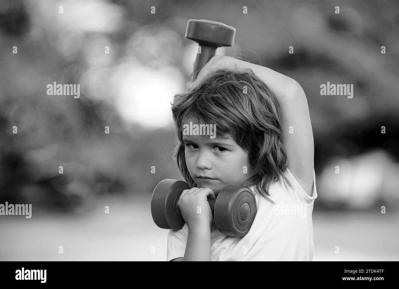Sport child boy with strong biceps muscles. Kids exercising fitness dumbbells. Strong little boy ...