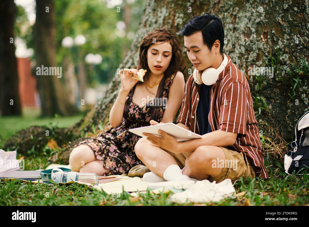 Young woman eating sandwich when listening to boyfriend explaining ...